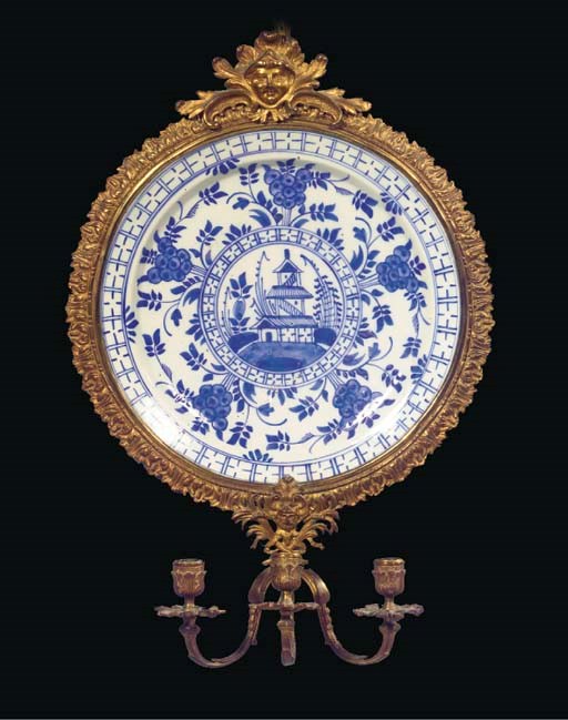 A gilt metal-mounted three-light wall sconce mounted with a Dutch Delft ...