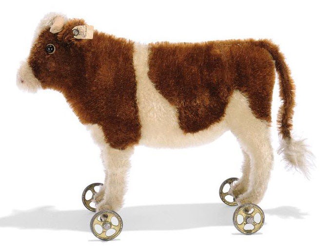 A STEIFF MOHAIR COW ON WHEELS, (1322), brown and white, black boot ...