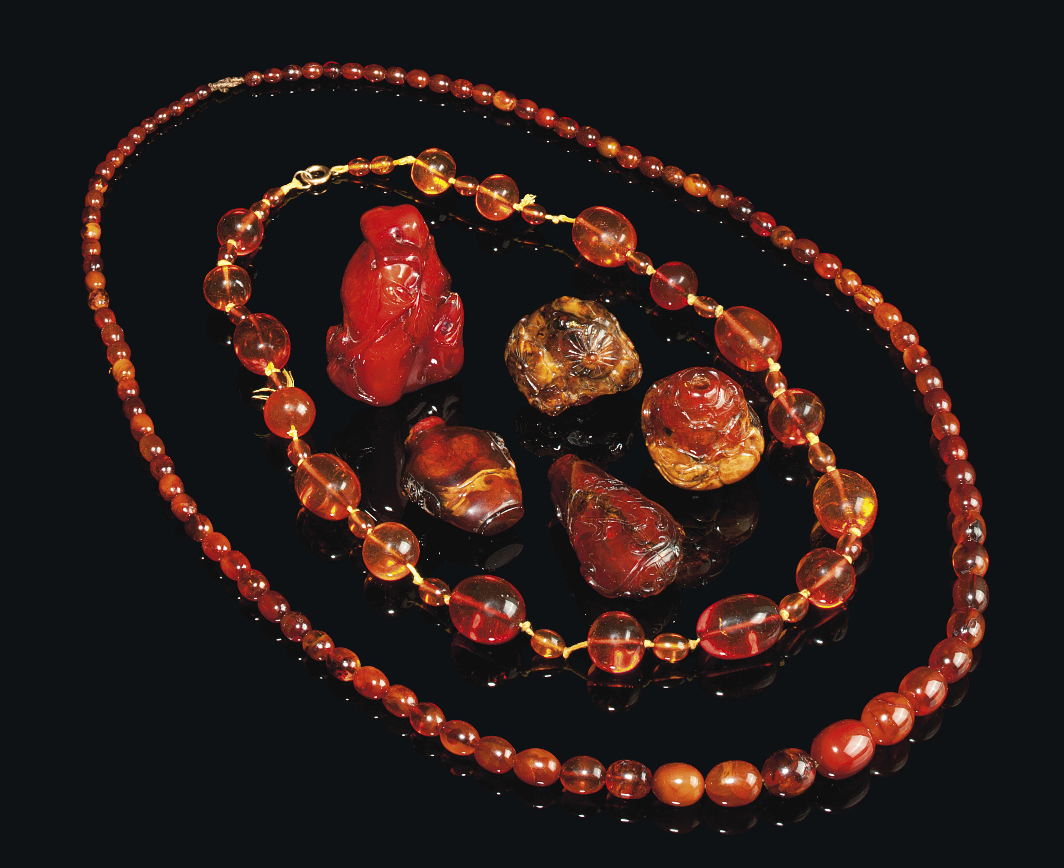 FIVE CHINESE AMBER CARVINGS AND TWO AMBER NECKLACES