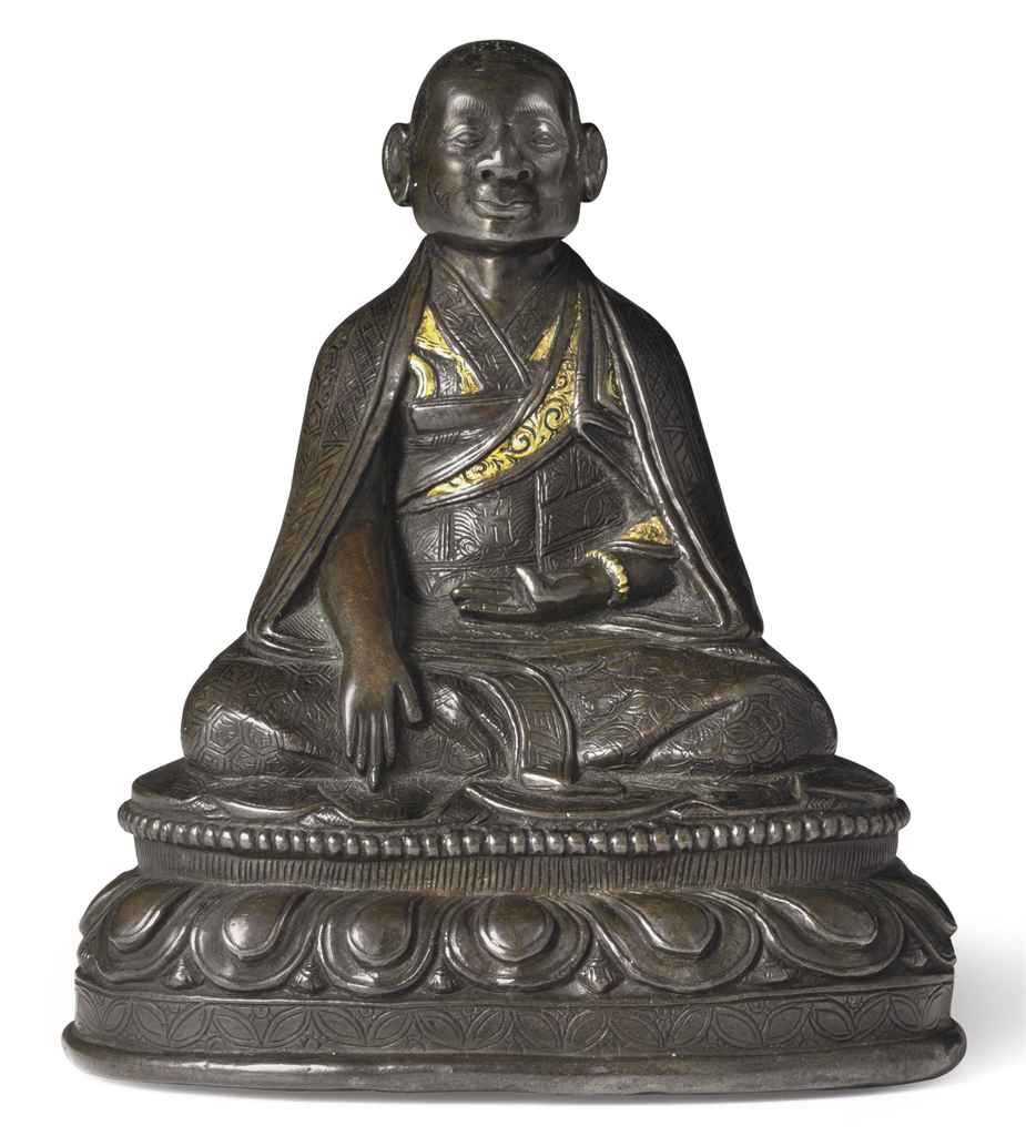 A bronze figure of a lama with gold inlay , TIBET, 15TH CENTURY ...