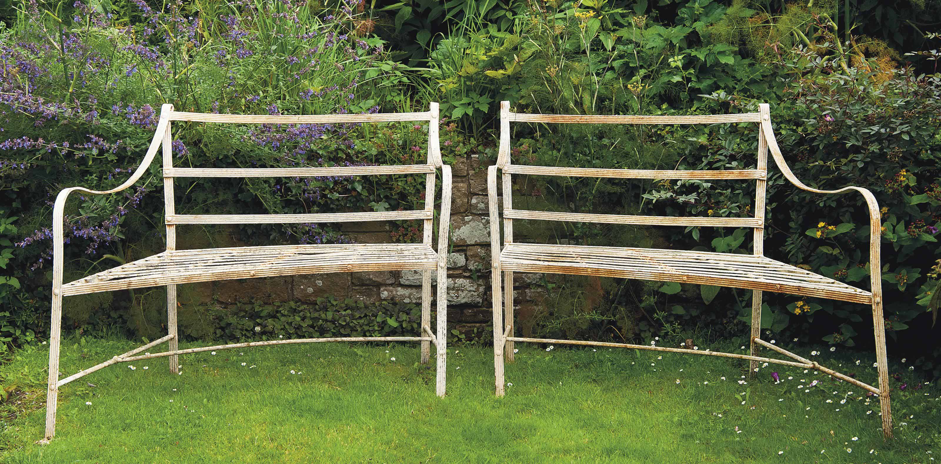 A PAIR OF CURVED WHITE-PAINTED WROUGHT-IRON GARDEN BENCHES