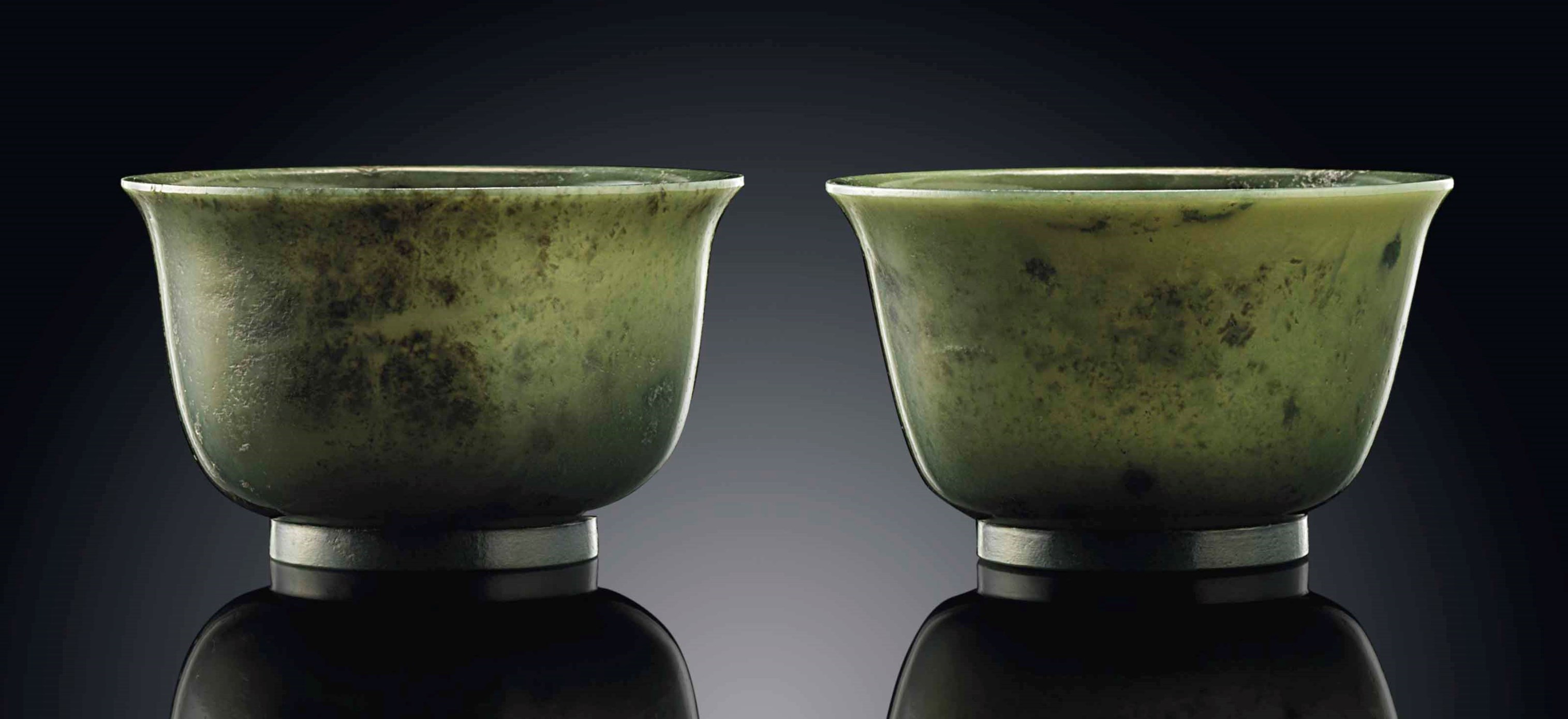 A PAIR OF SPINACH-GREEN JADE CUPS, QIANLONG INCISED SIX-CHARACTER SEAL ...