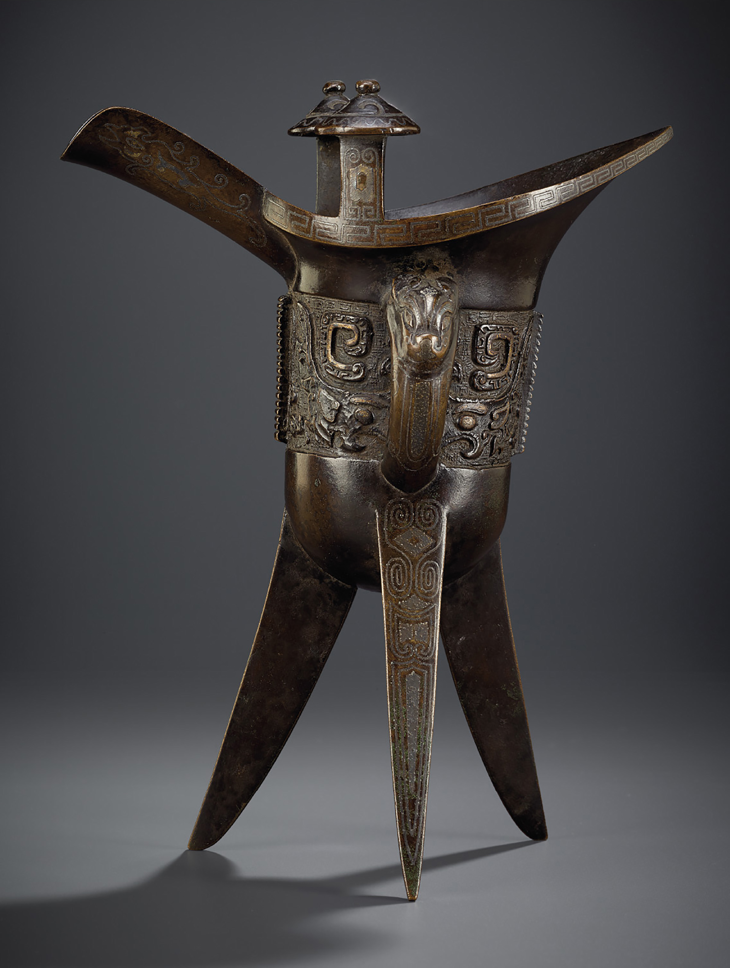 A SILVER-INLAID BRONZE TRIPOD WINE VESSEL, JUE
