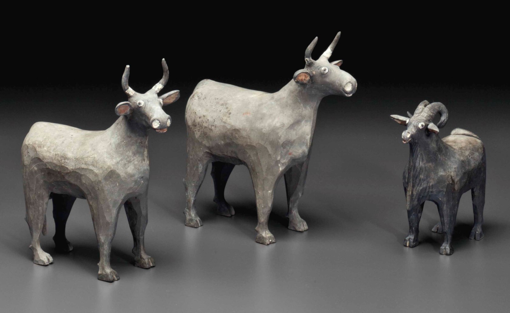 THREE UNUSUAL PAINTED GREY POTTERY FIGURES OF DOMESTIC ANIMALS, WARRING ...