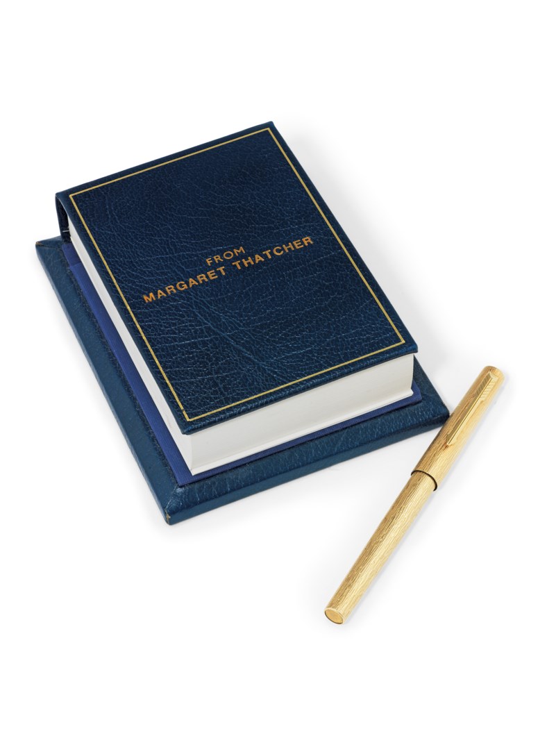 AN ENGRAVED GILT-METAL PEN AND A BLUE LEATHER DESK NOTEPAD, THE PEN BY ...