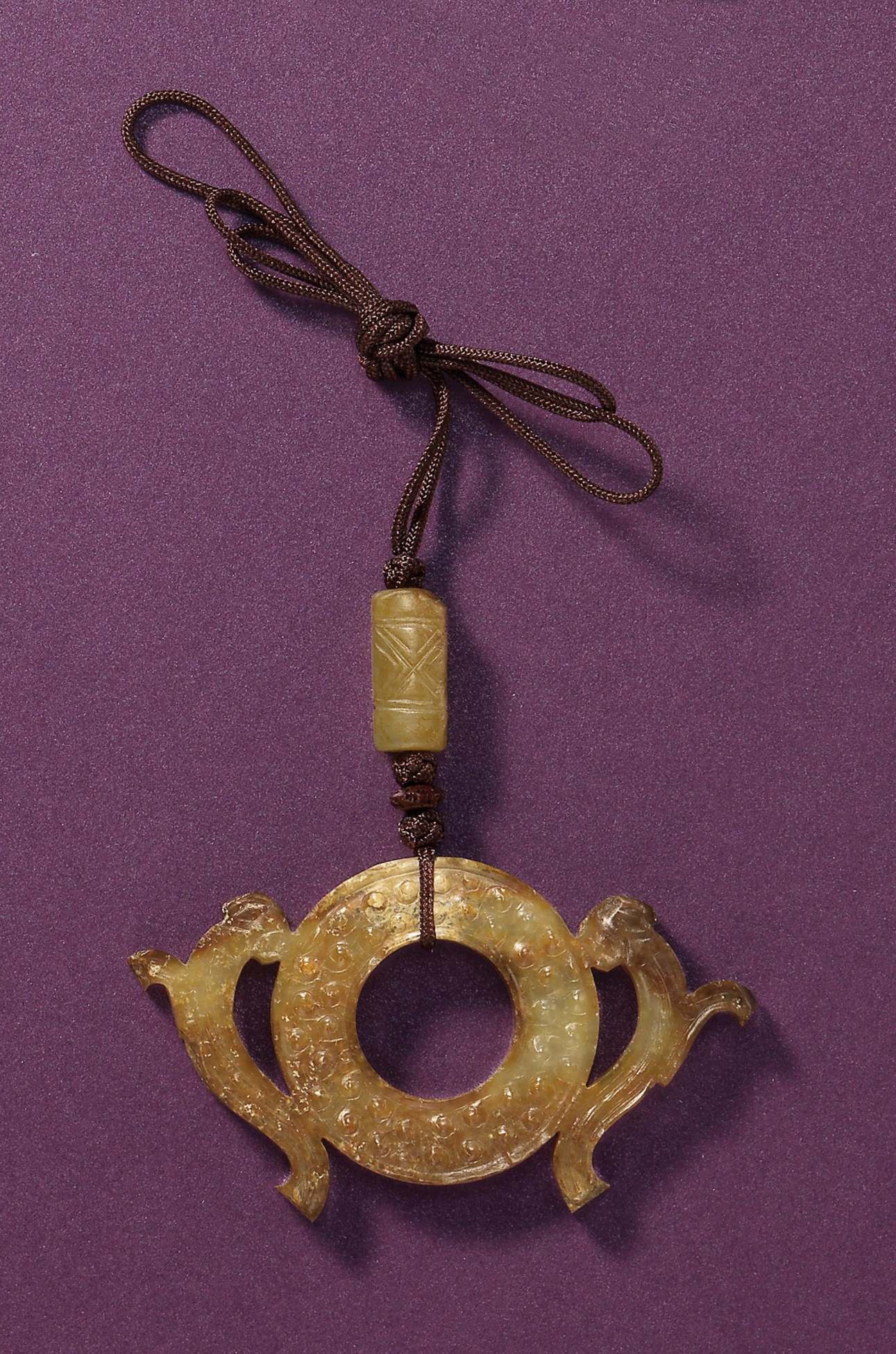 A WHITE AND RUSSET JADE DRAGON-HANDLED DISC, YUAN, SPRING AND AUTUMN ...