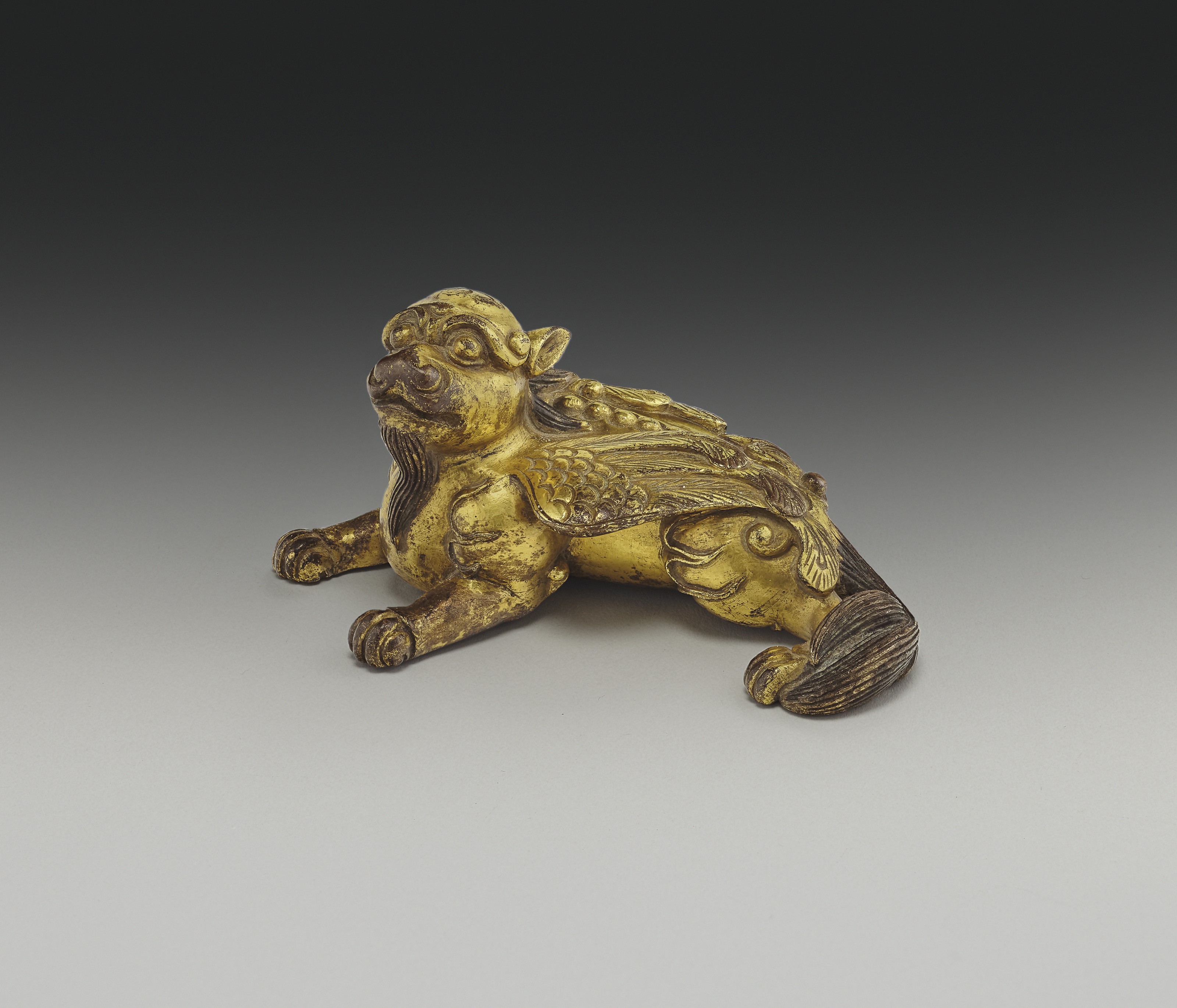 AN UNUSUAL SMALL GILT-BRONZE MYTHICAL BEAST-FORM WEIGHT