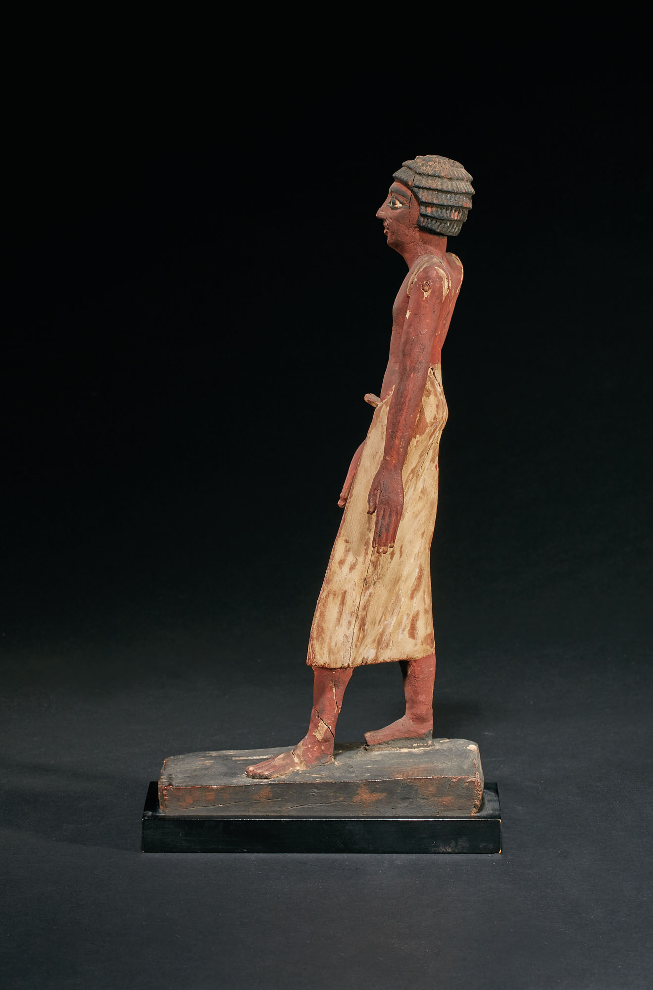 AN EGYPTIAN POLYCHROME WOOD FIGURE OF AN OFFICIAL