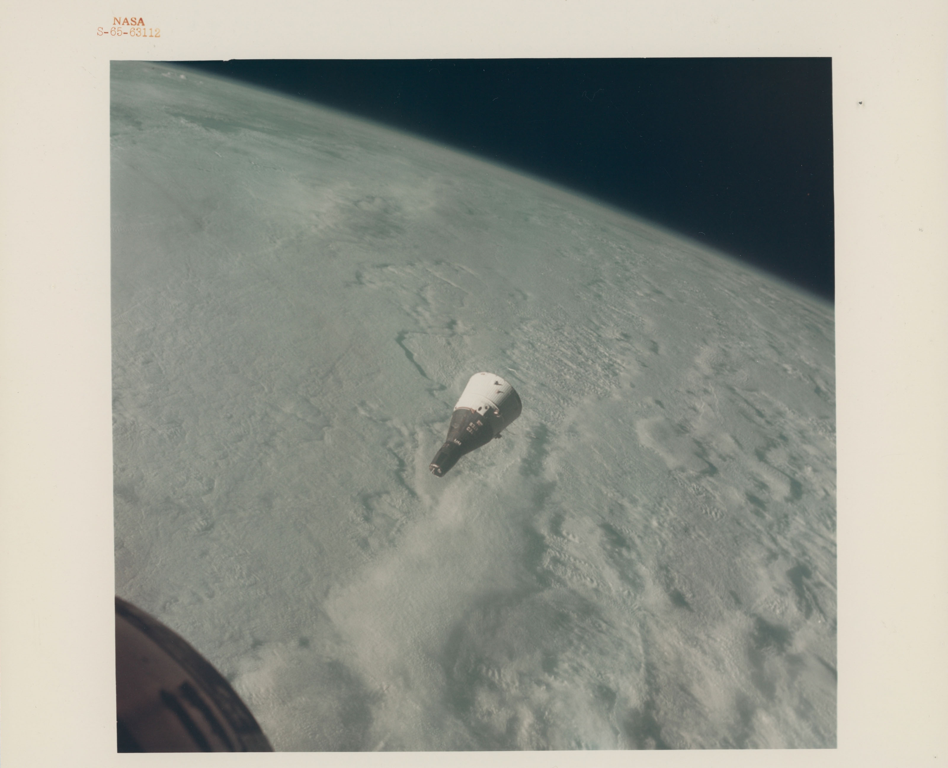 Gemini VII above the cloud-covered Earth; the spacecraft maneuvering ...