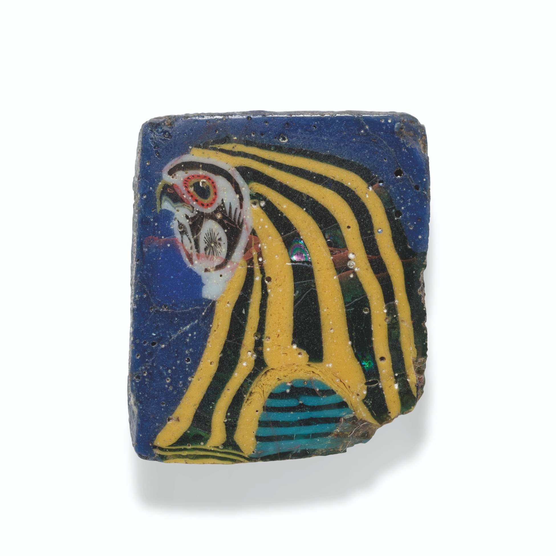 AN EGYPTIAN MOSAIC GLASS FALCON HEAD INLAY, PTOLEMAIC PERIOD, CIRCA 2ND ...