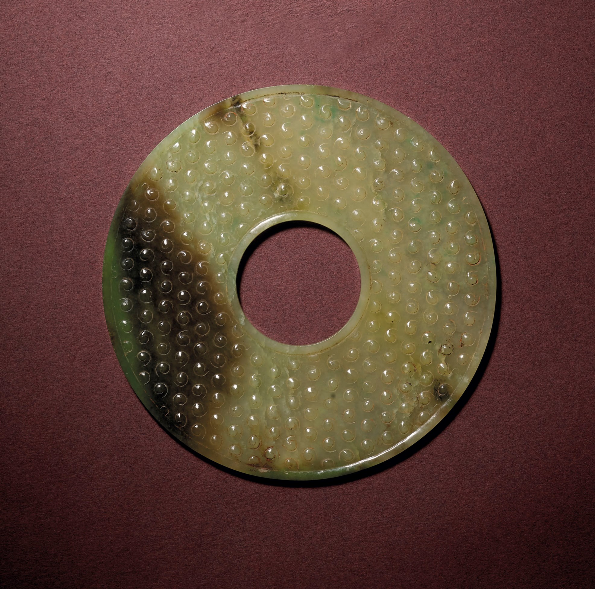 A PALE CELADON AND RUSSET JADE DISC, BI, MID WARRING STATES PERIOD ...