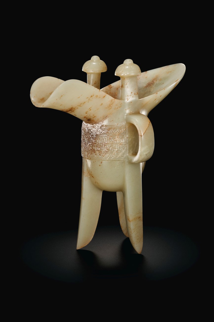 A RARE ARCHAISTIC PALE GREEN AND RUSSET JADE TRIPOD VESSEL, JUE
