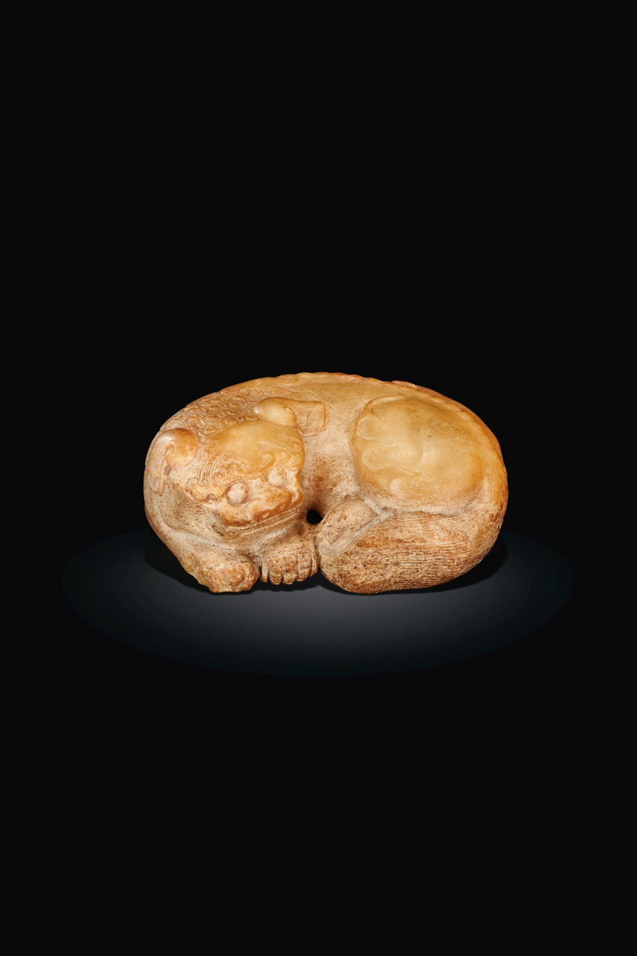 A YELLOWISH-BEIGE JADE OR HARDSTONE FIGURE OF A RECUMBENT MYTHICAL ...