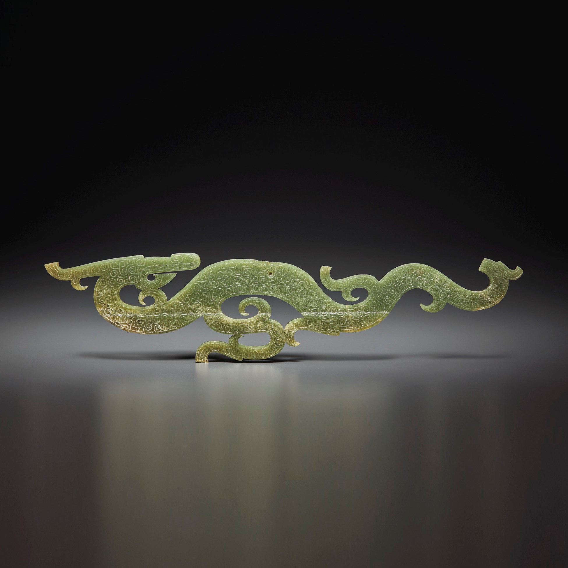 A LARGE YELLOWISH-GREEN JADE DRAGON-FORM PENDANT, WARRING STATES PERIOD ...
