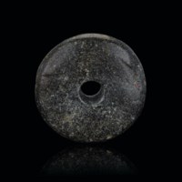 A GREEK BLACK STEATITE PERFORATED DISC WITH THREE HORSES, GEOMETRIC ...