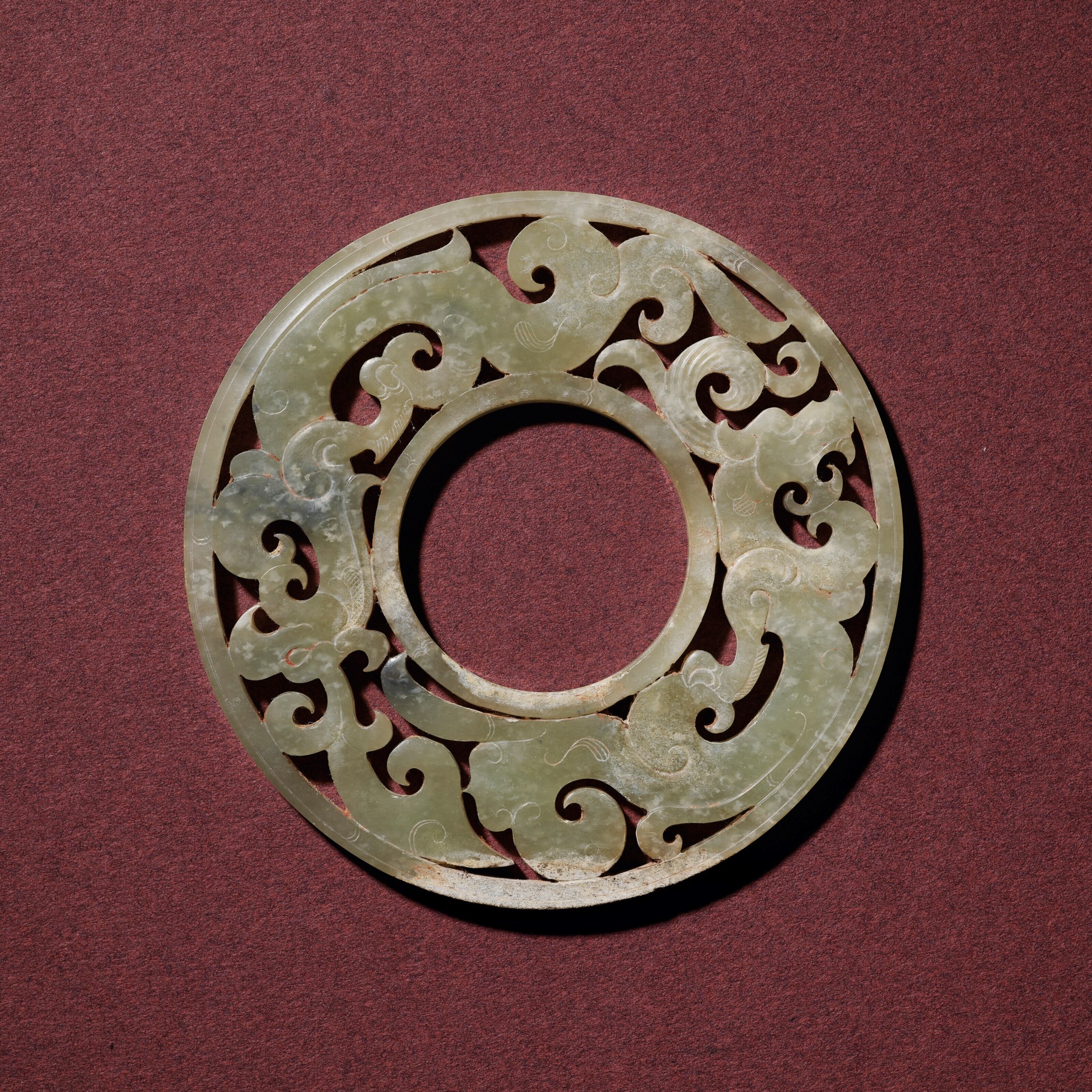 A PALE CELADON JADE RETICULATED ‘DRAGON AND PHOENIX’ DISC, BI, WESTERN ...