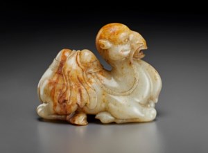 A FINELY CARVED PALE GREY AND RUSSET JADE FIGURE OF A RECUMBENT CAMEL ...