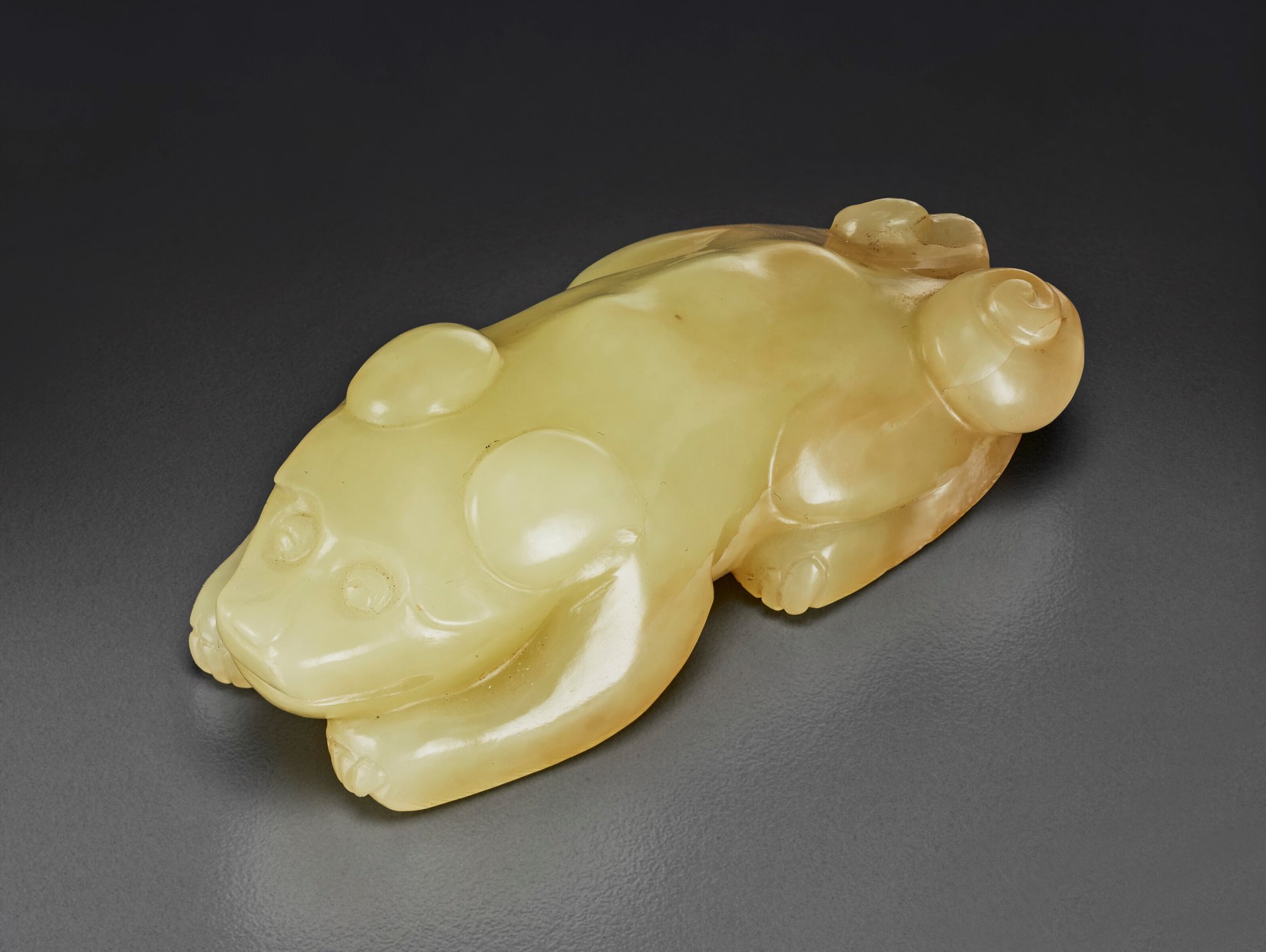 A PALE YELLOW JADE FIGURE OF A RECUMBENT DOG, QING DYNASTY, 17TH-18TH ...
