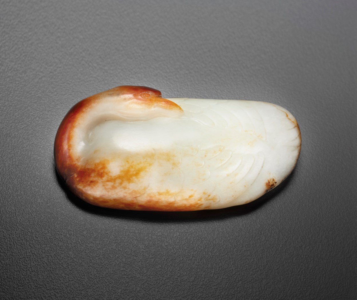 A WHITE AND RUSSET JADE FIGURE OF A RECUMBENT GOOSE, QING DYNASTY, 17TH ...