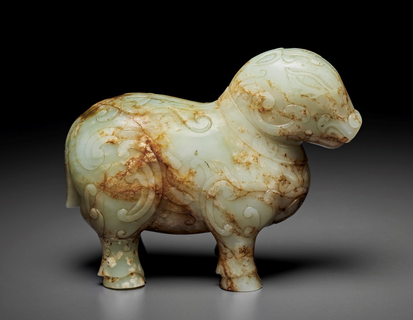 A PALE CELADON AND RUSSET JADE FIGURE OF A MYTHICAL BEAST, QING DYNASTY ...
