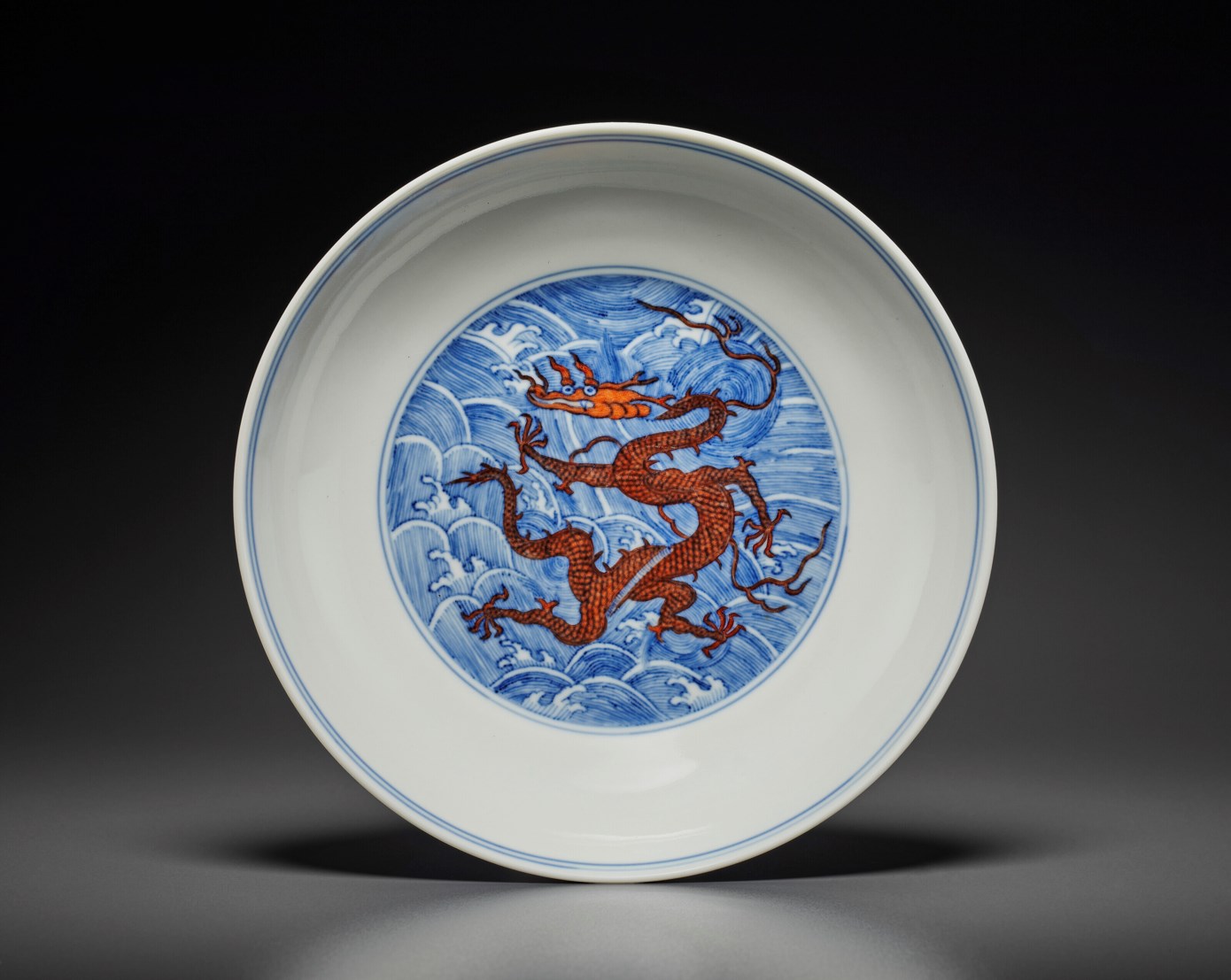 AN IRON-RED-ENAMELED BLUE AND WHITE 'DRAGON' DISH, QIANLONG SIX ...
