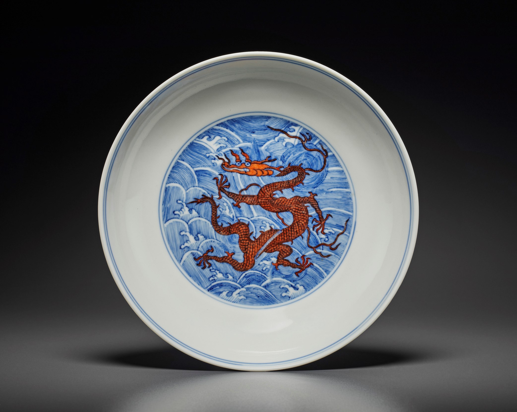 AN IRON-RED-ENAMELED BLUE AND WHITE 'DRAGON' DISH, QIANLONG SIX ...